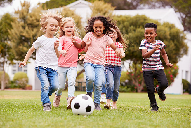 Kids Playing American Football In The Park